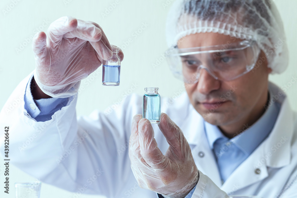 Young man scientist in glasses and gloves working on laboratory test of ...