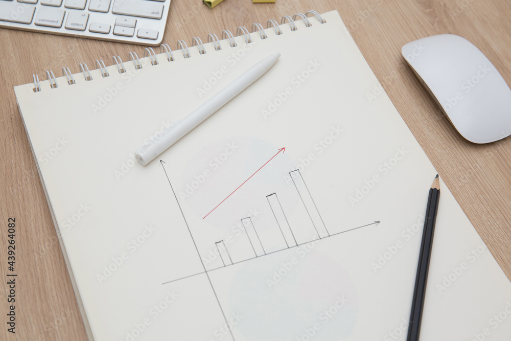 Drawing a graph of growth in a notebook on your desk at home.Wooden ...