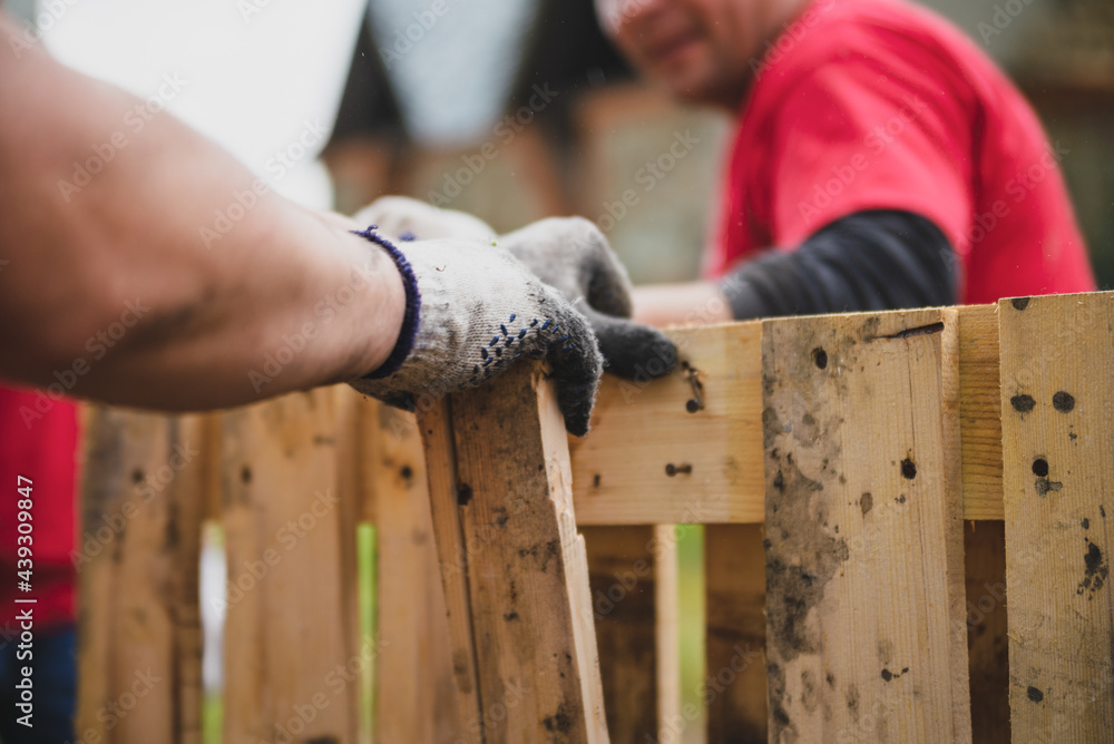 Working with wooden pallets. A man breaks a board in a pallet. Stock ...