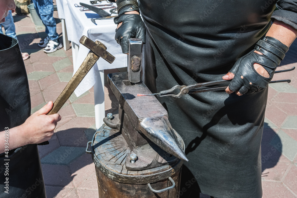 Master class in blacksmithing. The blacksmith teaches the boy to make a ...