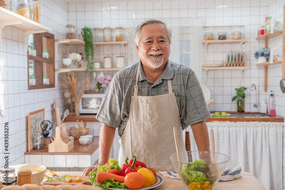 Happy Asian older man wears apron breakfast cooking in kitchen room at ...