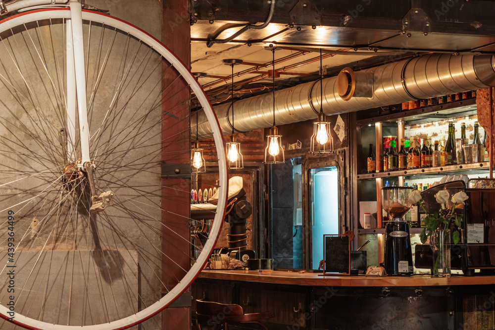 View on the wheel of vintage bicycle and a bar counter in a modern pub ...
