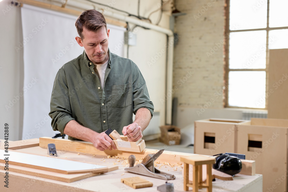 confident male carpenter is grinding raw wood in carpentry diy workshop ...