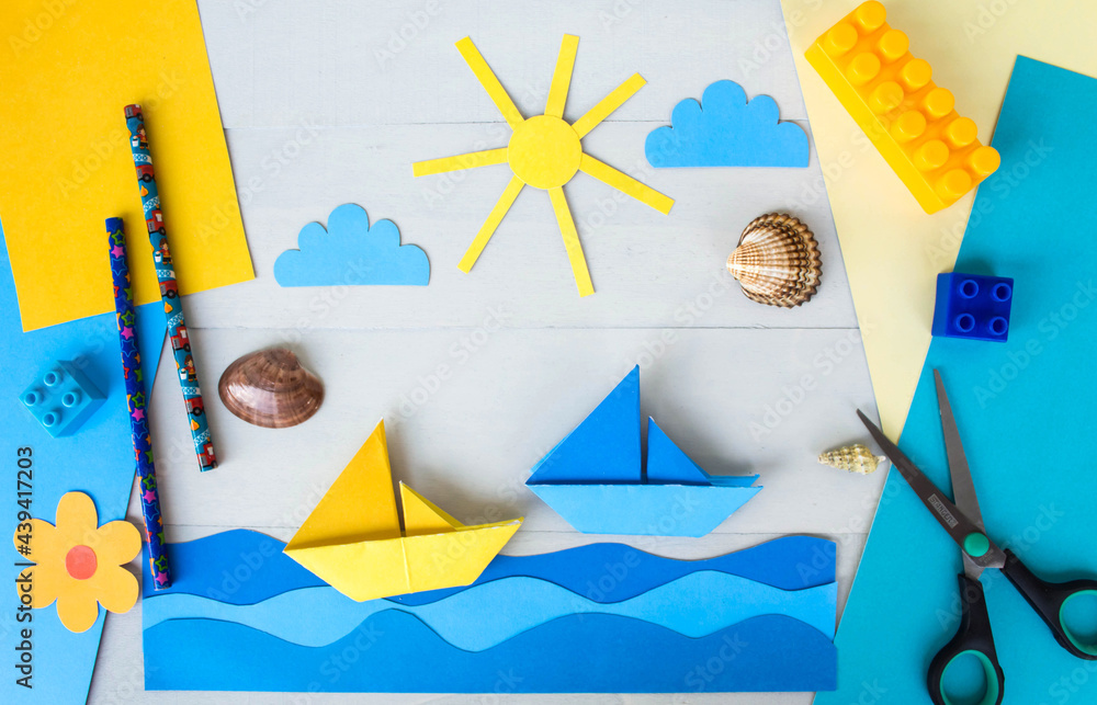 Craft Paper ship, waves, sun, clouds. Scissors, paper, seashells on a ...