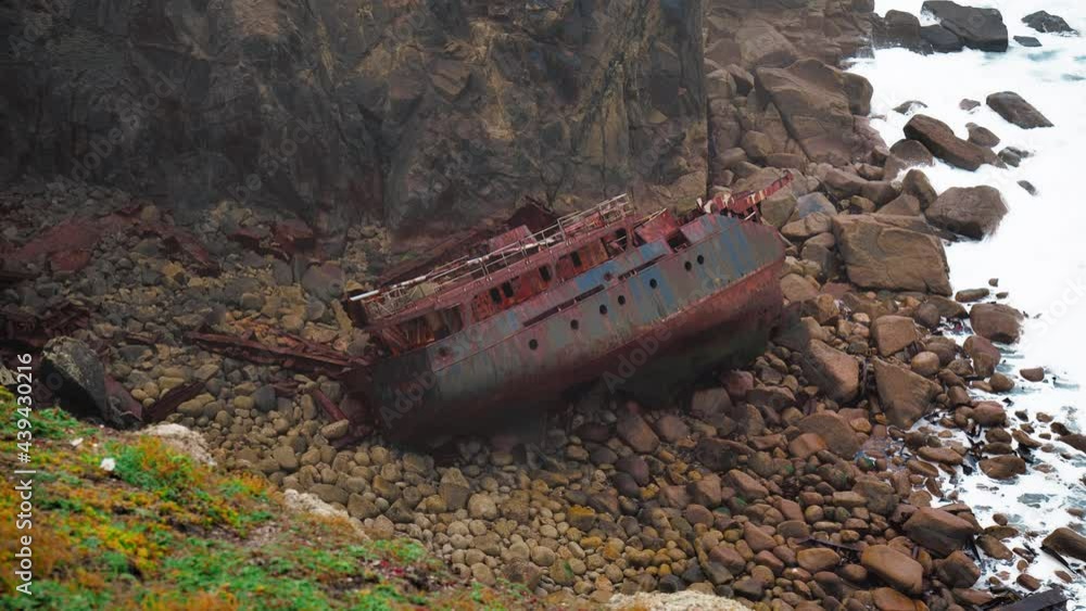 A dramatic old abandoned ship being crushed by waves and rusting on the ...
