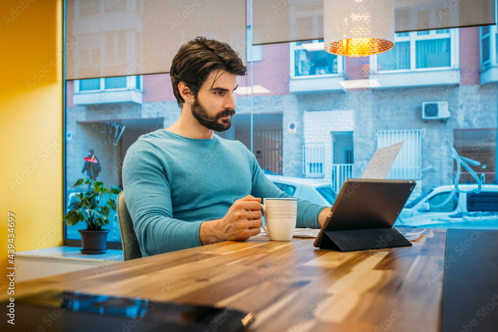 Serious man using laptop and drinking beverage Stock Photo | Adobe Stock