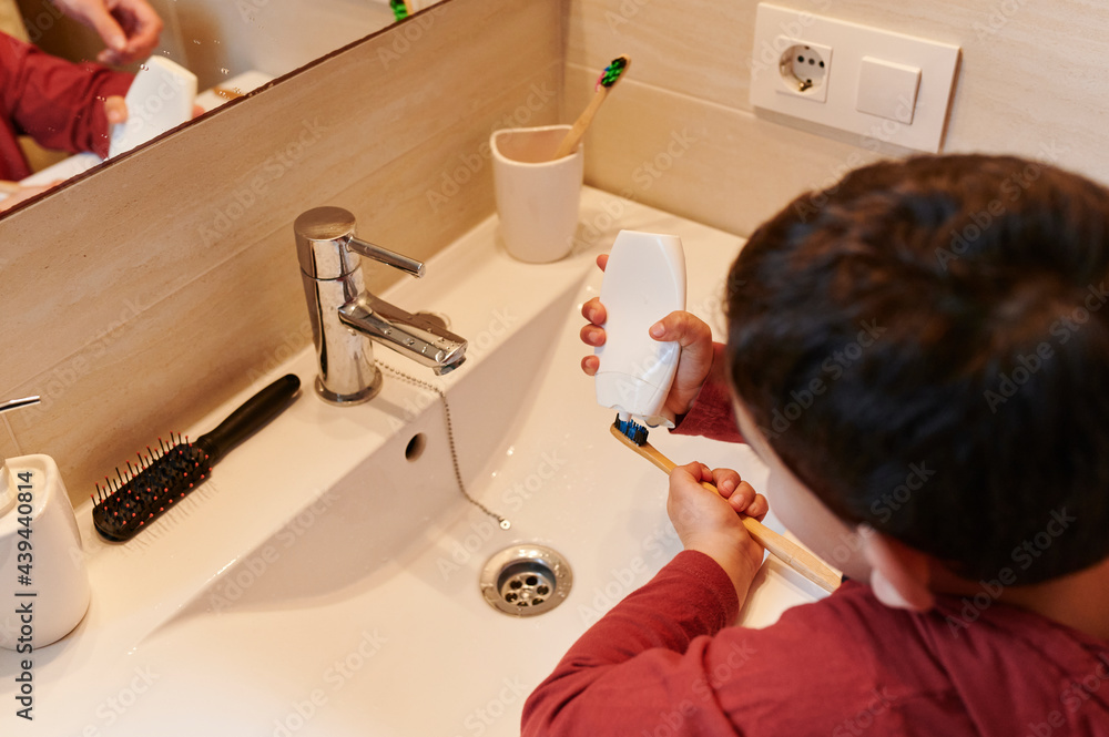 Boy putting toothpaste on his toothbrush Stock Photo | Adobe Stock