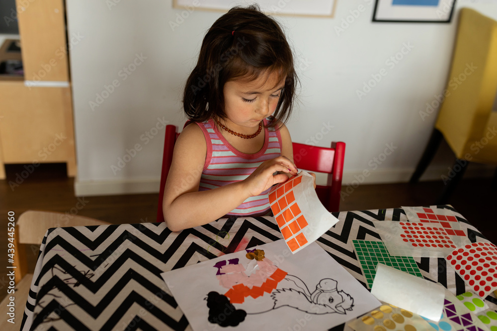 Little girl placing stickers on a picture at home Stock Photo | Adobe Stock