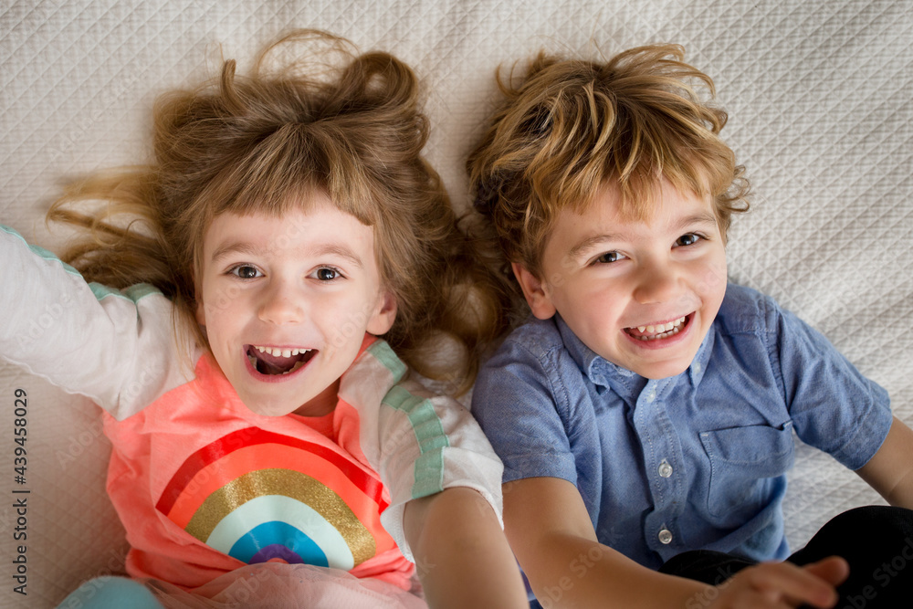 Portrait of laughing brother and sister laying on a bed Stock Photo ...