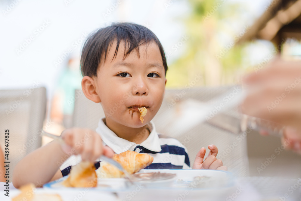 Asian toddler boy eating croissant with chocolate lunch in the school ...