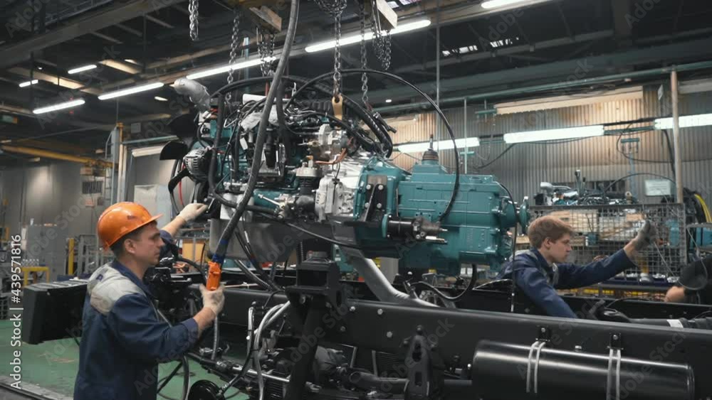 Factory Workers Lower Automobile Motor To Workplace Using Control ...