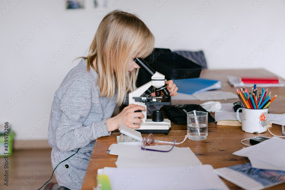 young girl looking through microscope Stock Photo | Adobe Stock