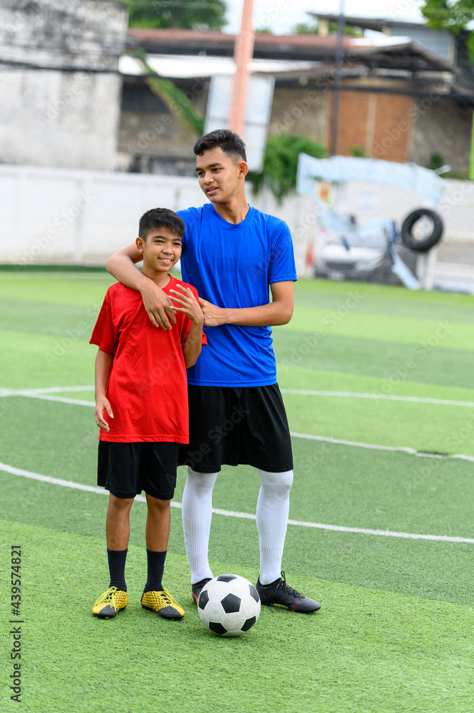An older brother and younger brother stand in the middle of a football ...