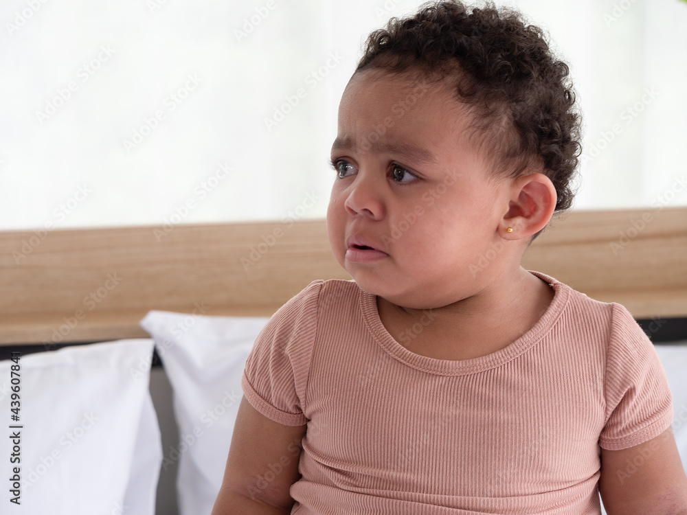 Portrait of sad dark-skinned child girl crying in the bedroom against ...