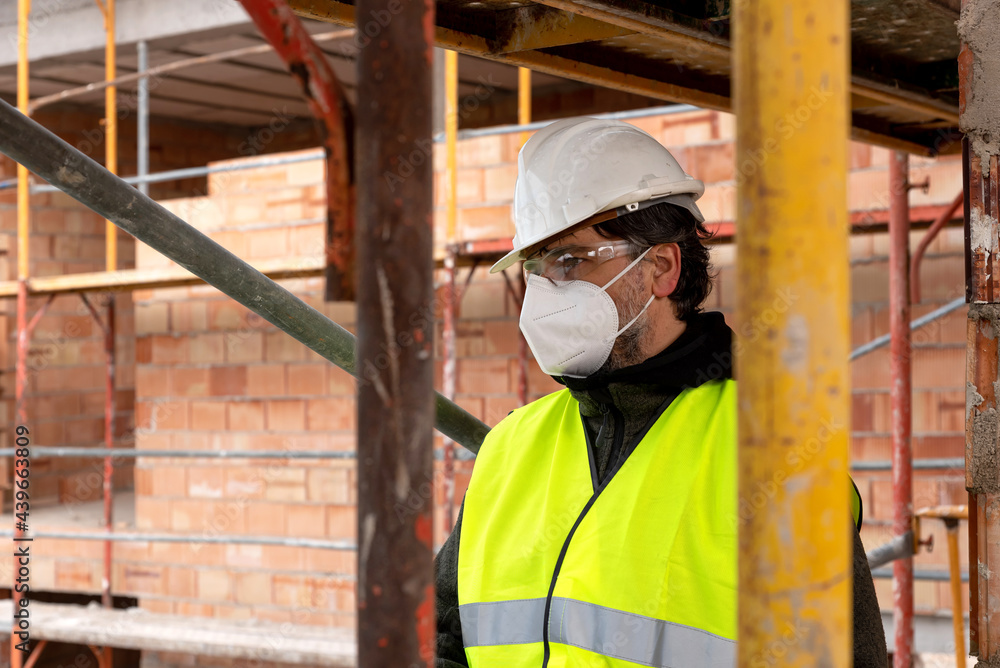 Workman in hardhat and protective mask working on construction site ...
