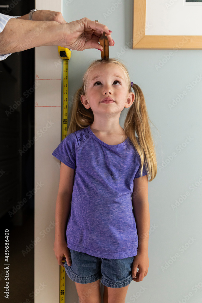 Young Girl Measuring her height with ruler Stock Photo | Adobe Stock