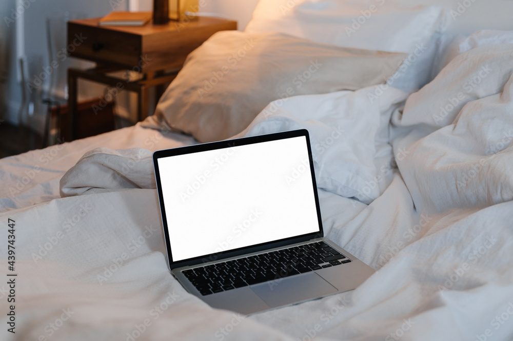 Modern laptop with white screen on bed Stock Photo | Adobe Stock