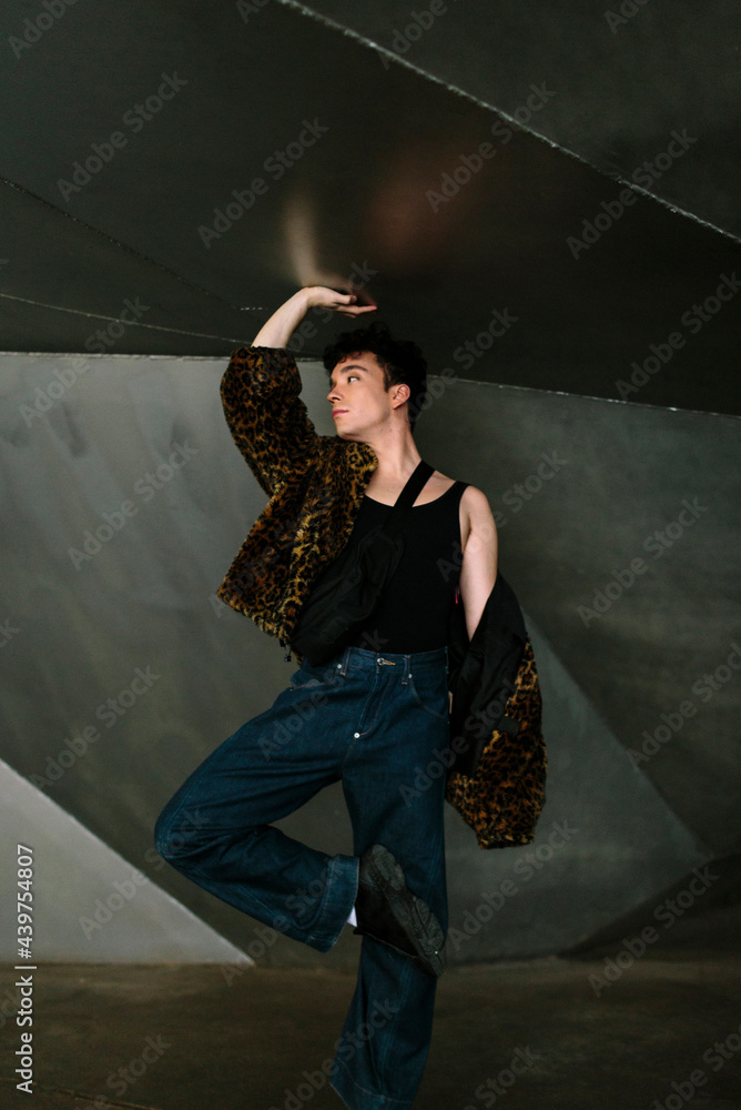 Young stylish non-binary person posing in dance position over grey ...