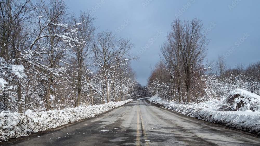Typical view of US backroad motorway after a snow storm between forests ...