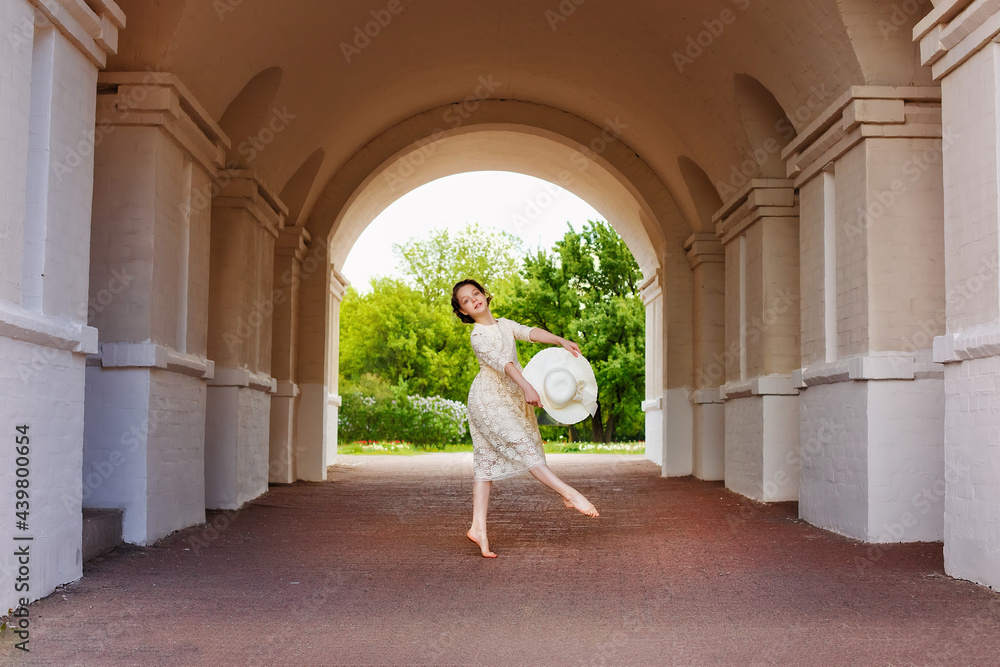 A graceful ballerina girl poses in an ancient street architectural arch ...