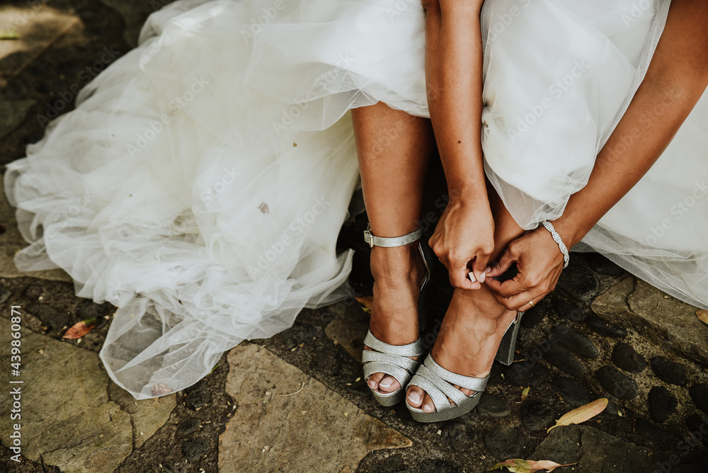 Bride putting on her shoes on her wedding day outdoors Stock Photo ...