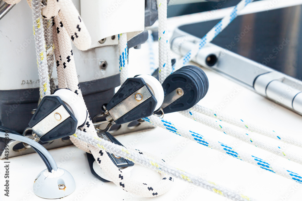 Part of the mast and hull of a sailing yacht, with multi-colored ropes ...