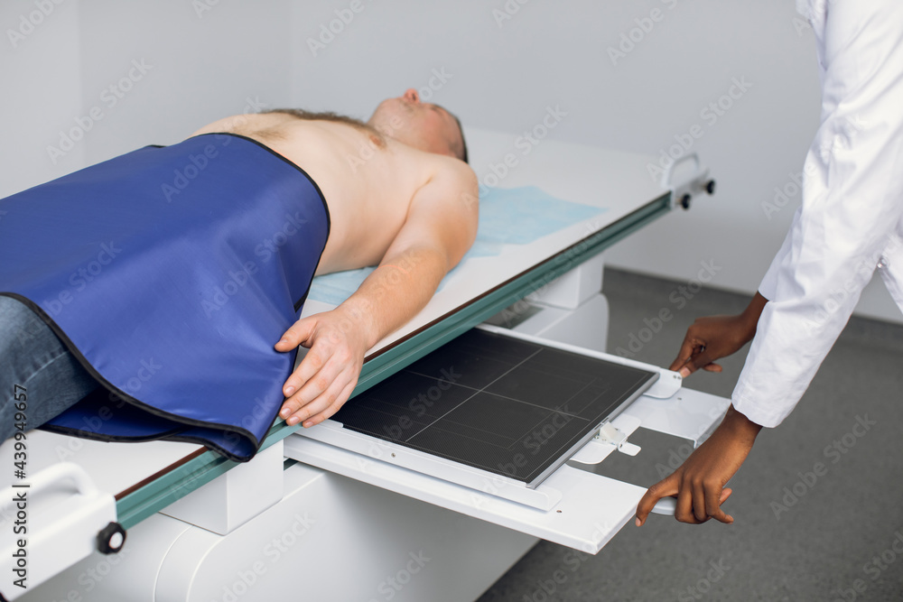 Young Caucasian man lying on the machine table during X-Ray scanning ...