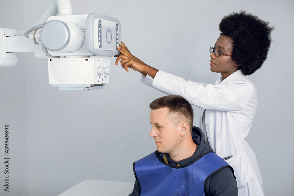 Young afro american female radiologist technician, setting up the ...