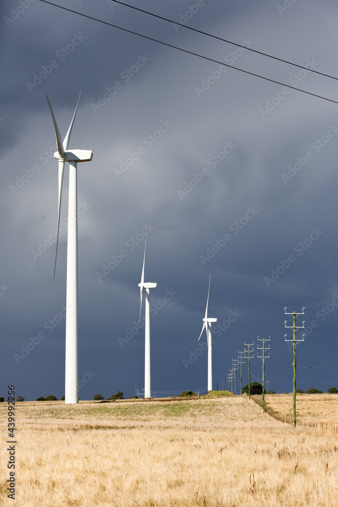 Wind turbines and power lines in paddock with incoming storm Stock ...