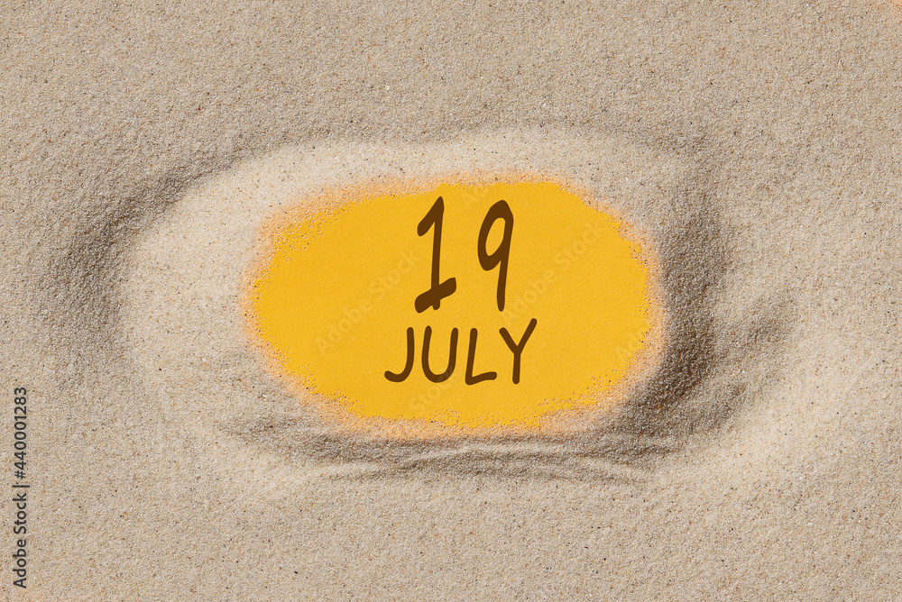 July 19. 19th day of the month, calendar date. Hole in sand. Yellow ...