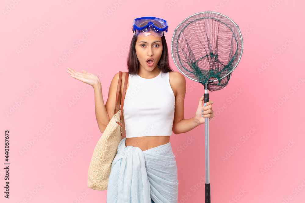 young fisher woman looking surprised and shocked, with jaw dropped ...