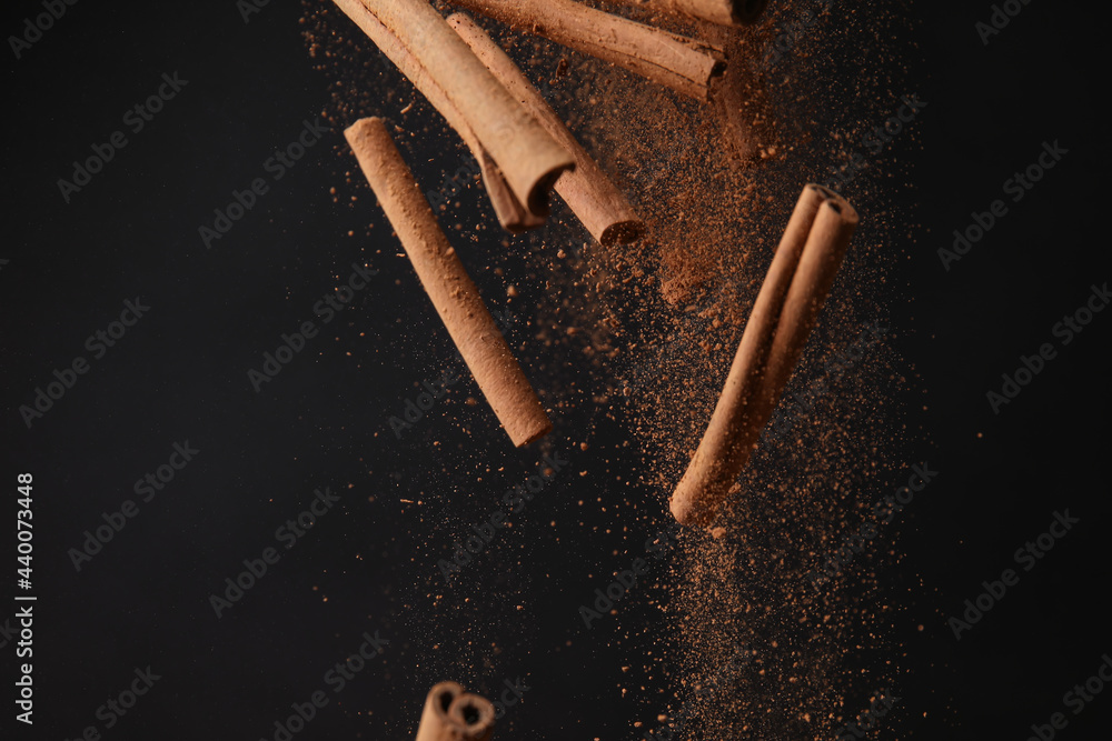 Falling cinnamon sticks and powder on dark background Stock Photo ...