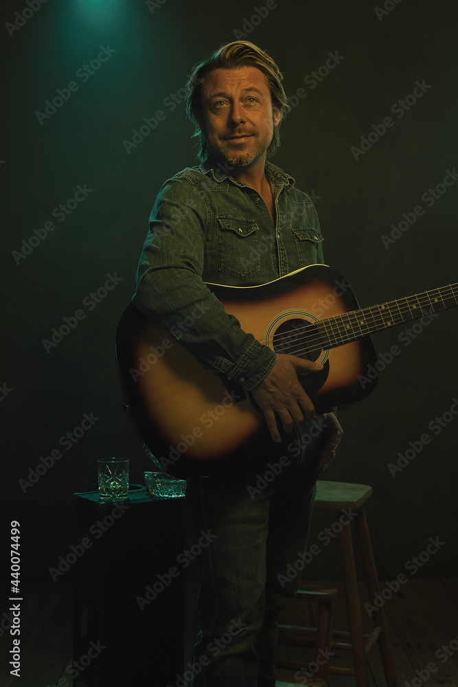 Country and western musician in jeans and denim shirt stands with an ...
