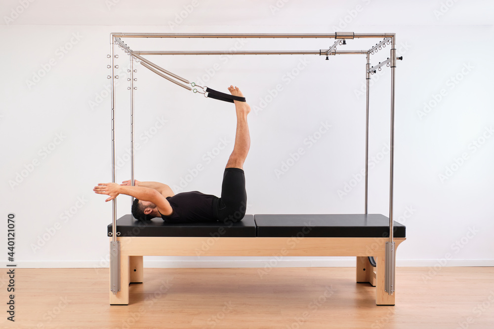 Mid adult man lying down with legs raised on trapeze table while ...