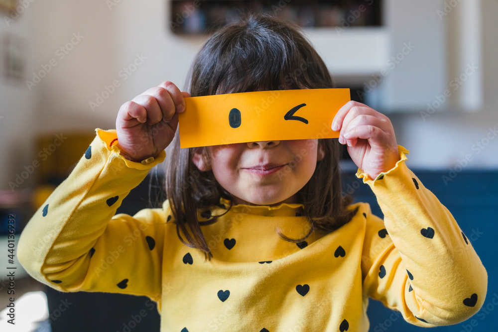 Girl holding yellow paper with winking emoticon at home Stock Photo ...