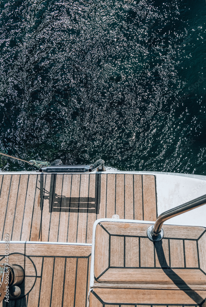 view of water surface from deck of the yacht. Wooden boat deck and ...