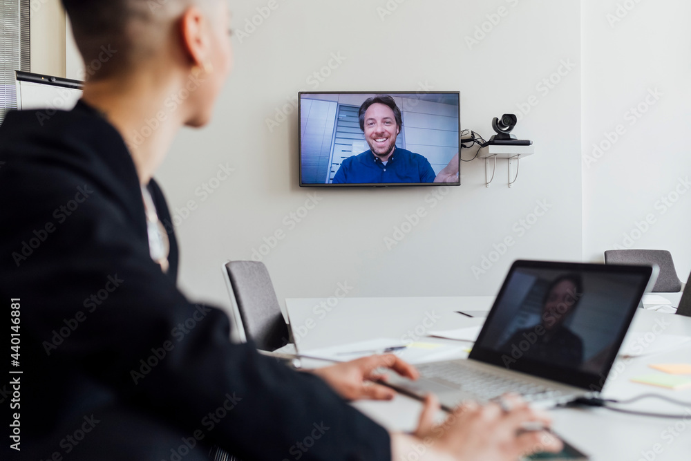 Businesswoman attending meeting with colleague through video call on ...