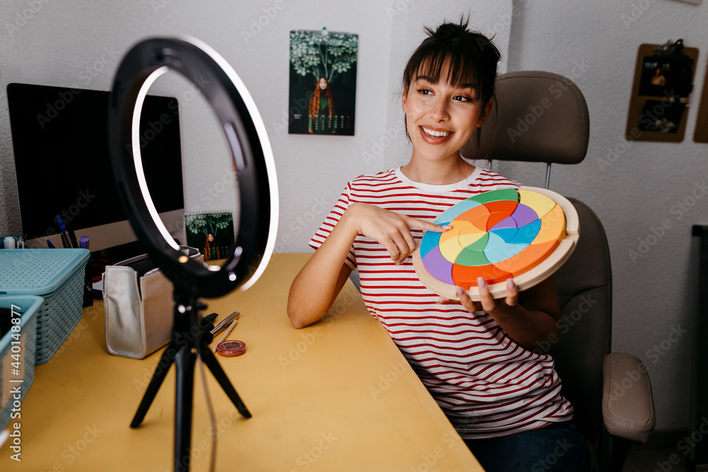 Female influencer seen through ring light while holding multi colored ...