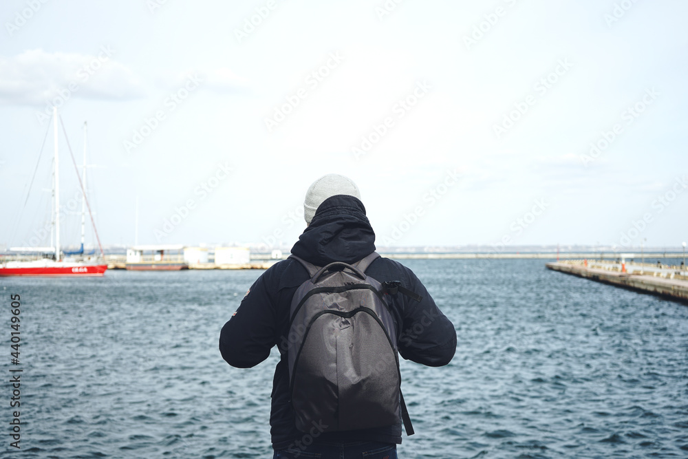 A man stands with his back to the camera on a background of the sea ...
