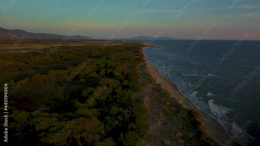 Cinematic aerial drone footage flying backwards above a sandy sunset ...