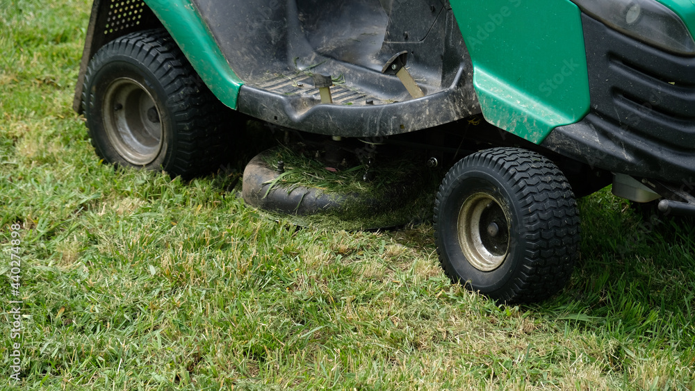 Green grass trimming with lawn mower. Tractor mowing grass in a public ...