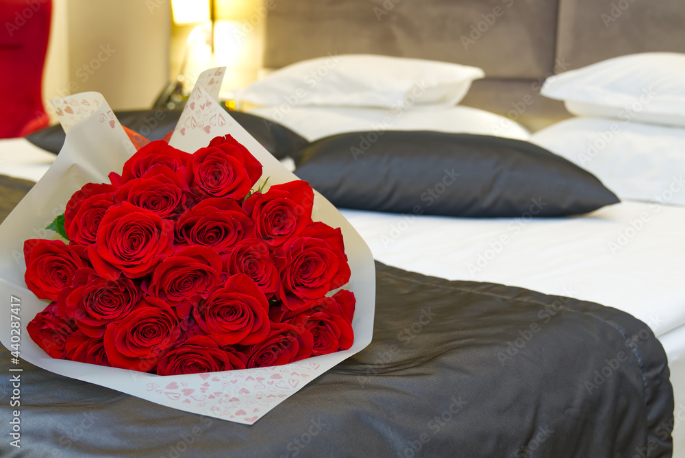 Bouquet of red roses on the bed in a hotel room. Romantic meeting of ...