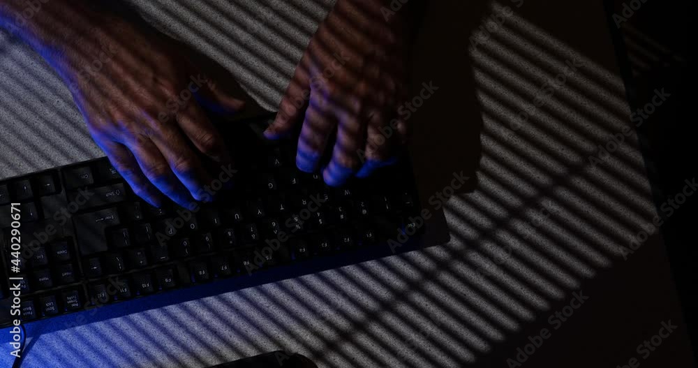 Hacker or coder typing in an overhead shot with colored lighting (red ...