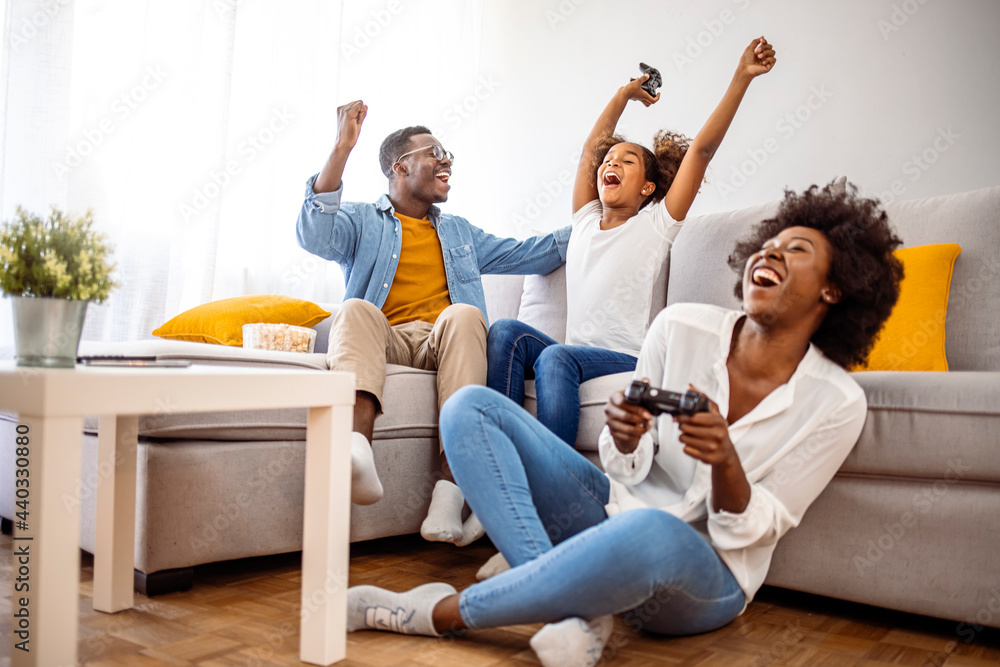 Smiling family sitting on the couch together playing video games ...