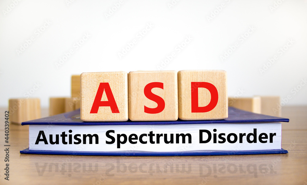 ASD, autism spectrum disorder symbol. Wooden cubes on book with words ...