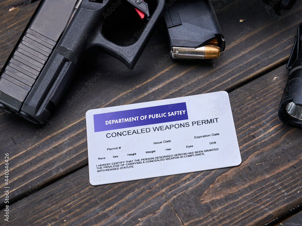 Concealed Carry Permit sitting on a table next to semi-automatic ...