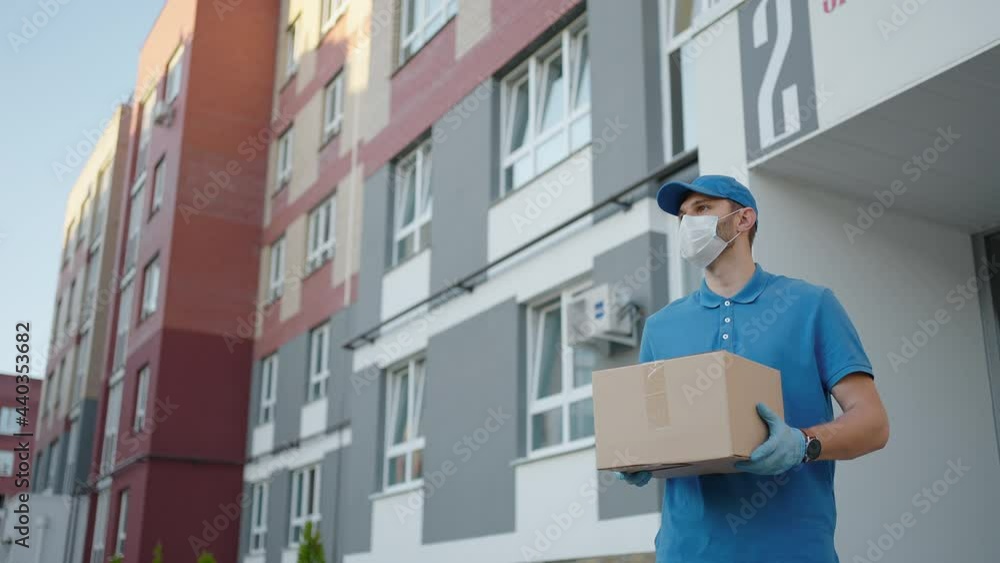 Video „An young mailman courier with a protective mask and gloves is ...