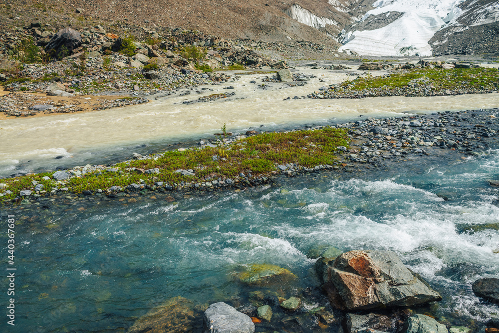 Sunny alpine landscape with confluence of two various mountain rivers ...