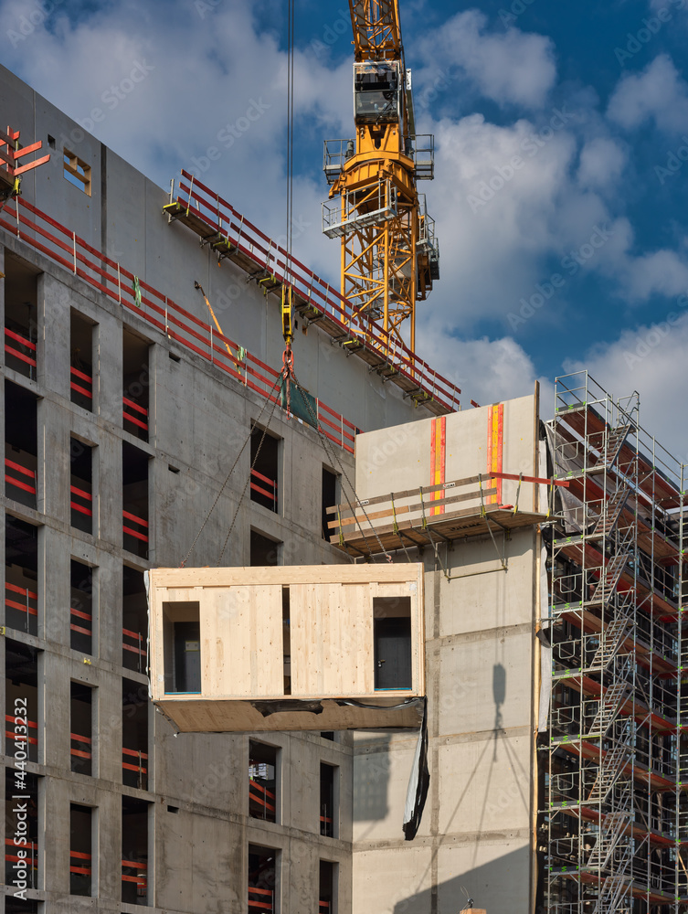 Crane lifting a wooden building module to its position in the structure ...