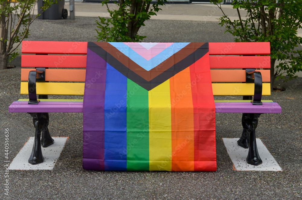 A bench painted in rainbow pride flag colors near Sheridan collage ...
